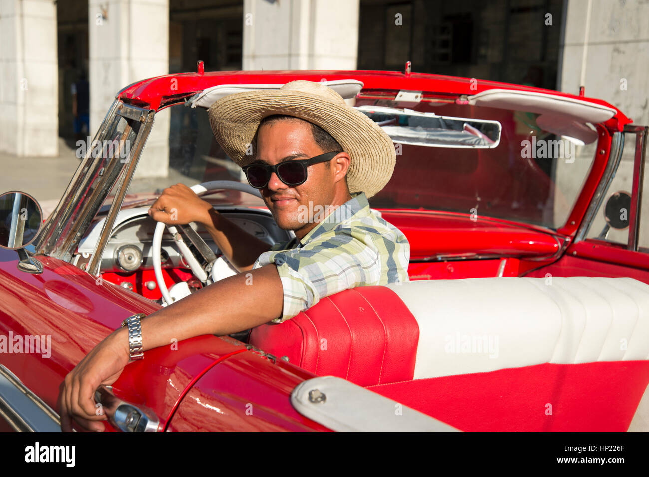 Classic 1950's red American car with Cuban man wearing a cowboy hat ...