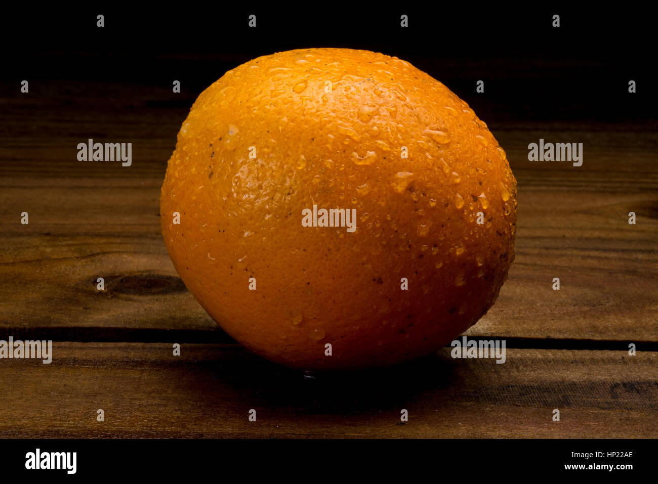 single wet orange on a wood table Stock Photo - Alamy