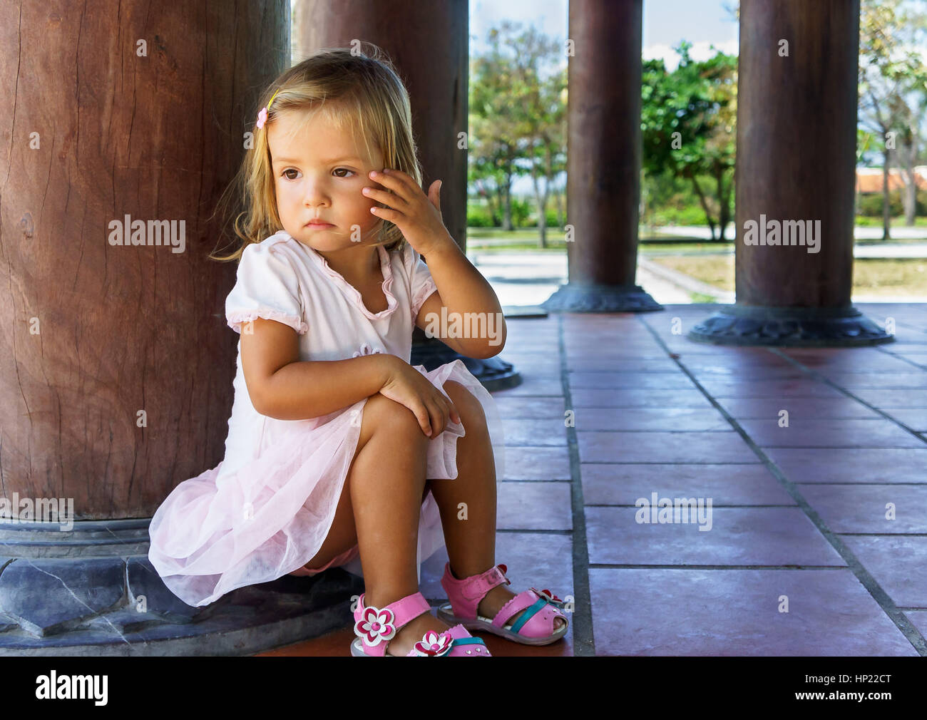 little girl sitting near the column Stock Photo - Alamy