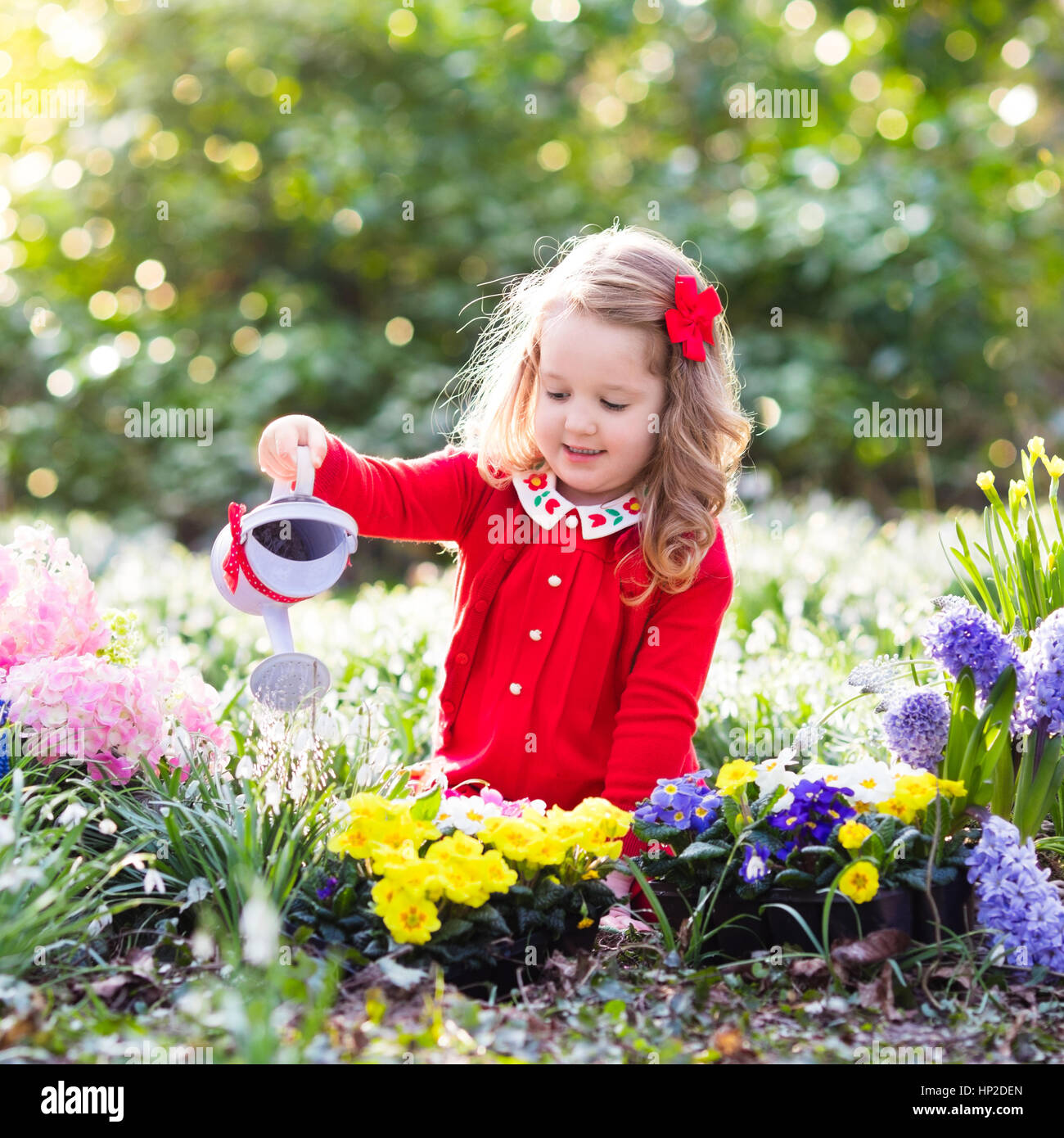 Child planting spring flowers in sunny garden. Little girl gardener ...