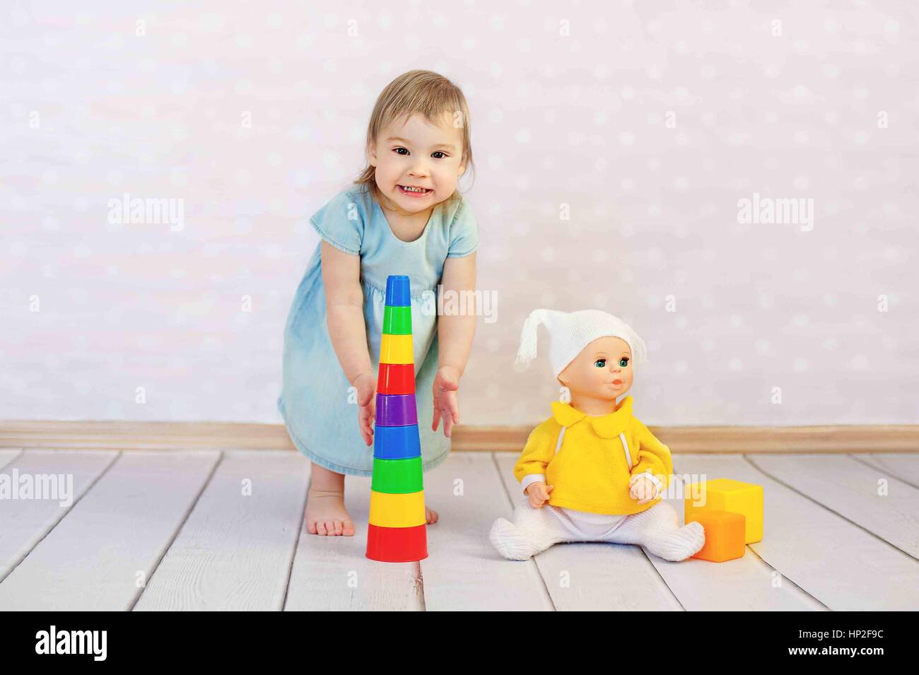 Cute little girl playing with toys sitting on the floor on wooden ...