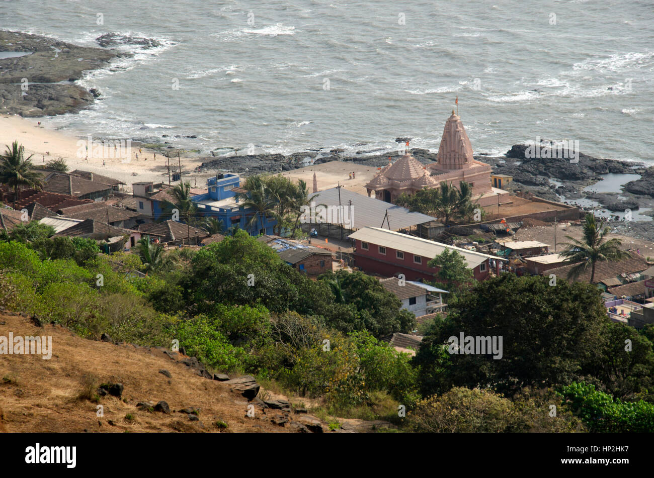 Carved temple and rooftop of houses, village near Anjarle, Konkan ...