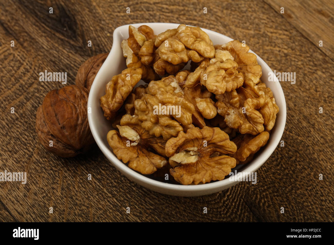 Opened walnuts in the bowl over wooden background Stock Photo - Alamy