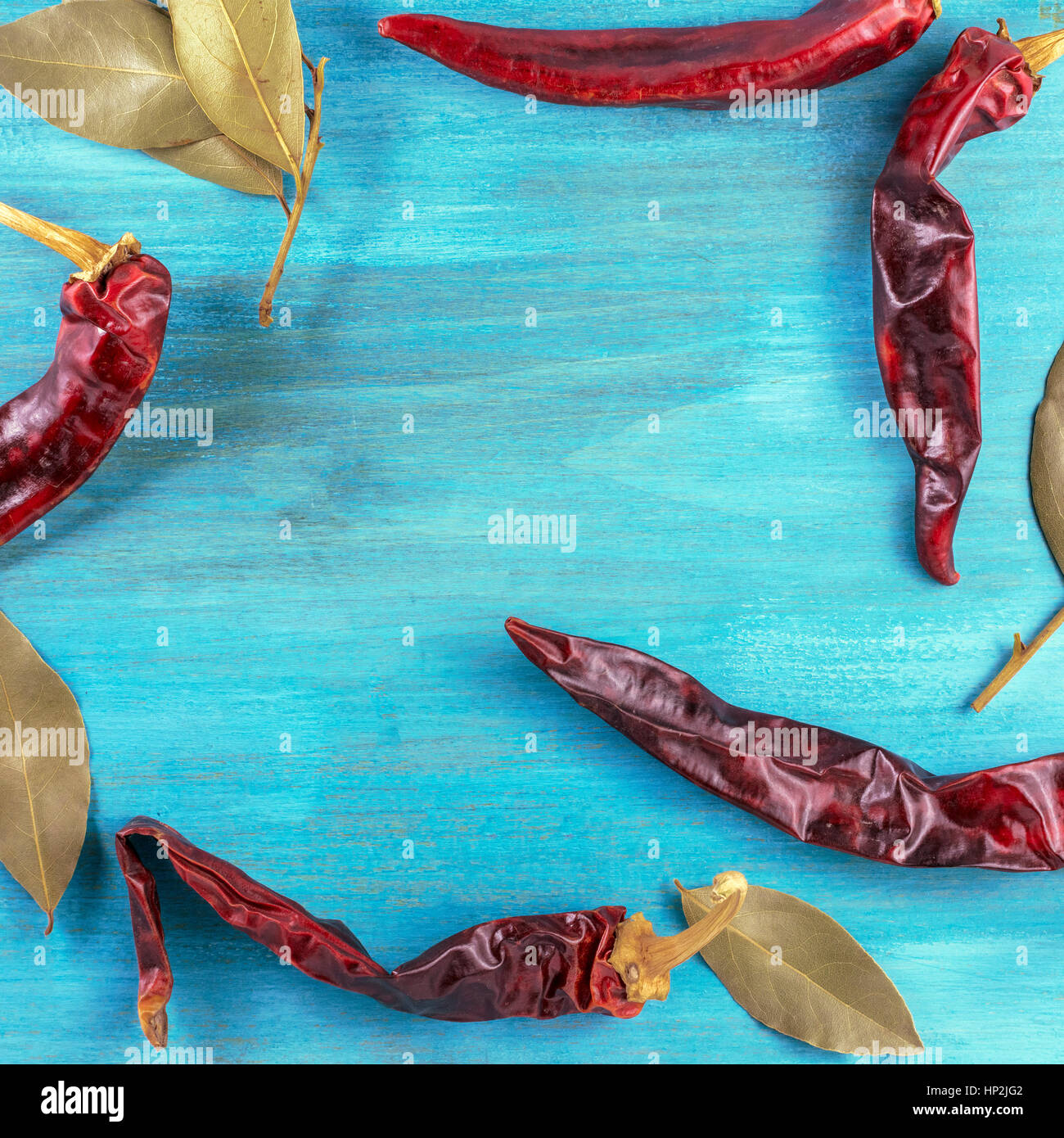 A square photo of chili peppers and bay leaves on a vibrant turquoise ...