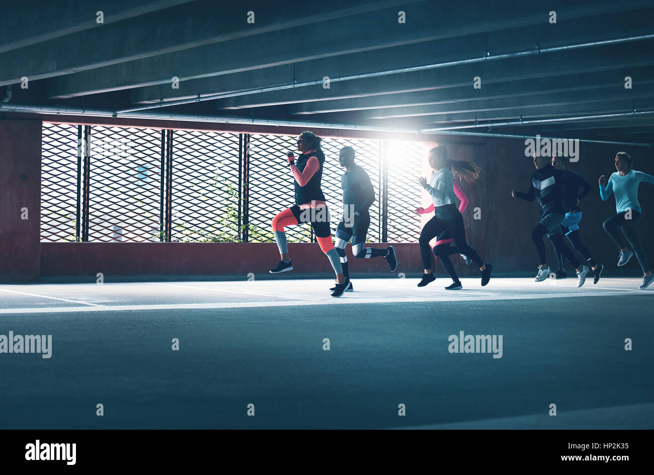 Side view of several people doing running exercises against huge window ...