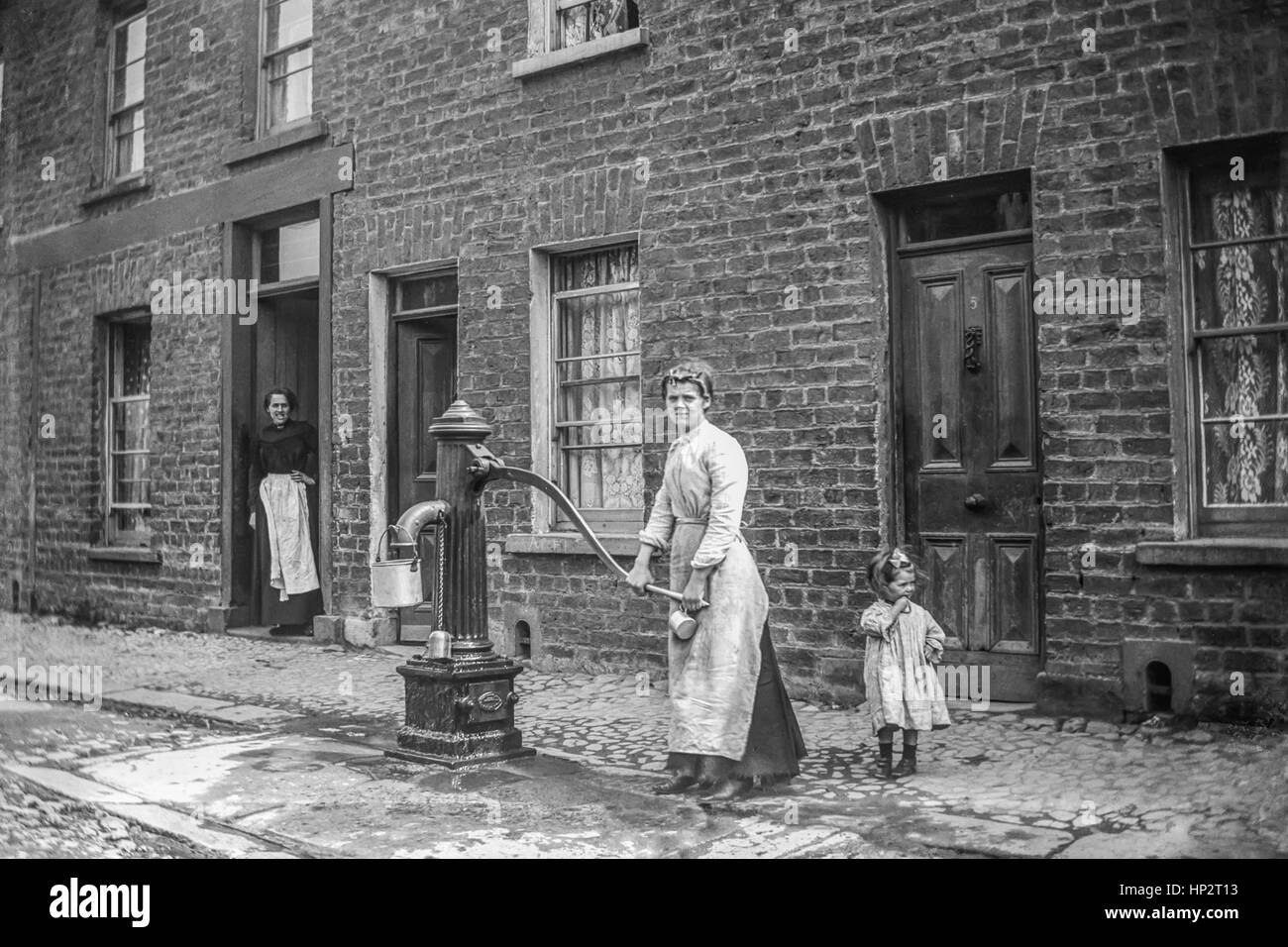 Edwardian lady wearing an apron and accompanied by a small child ...