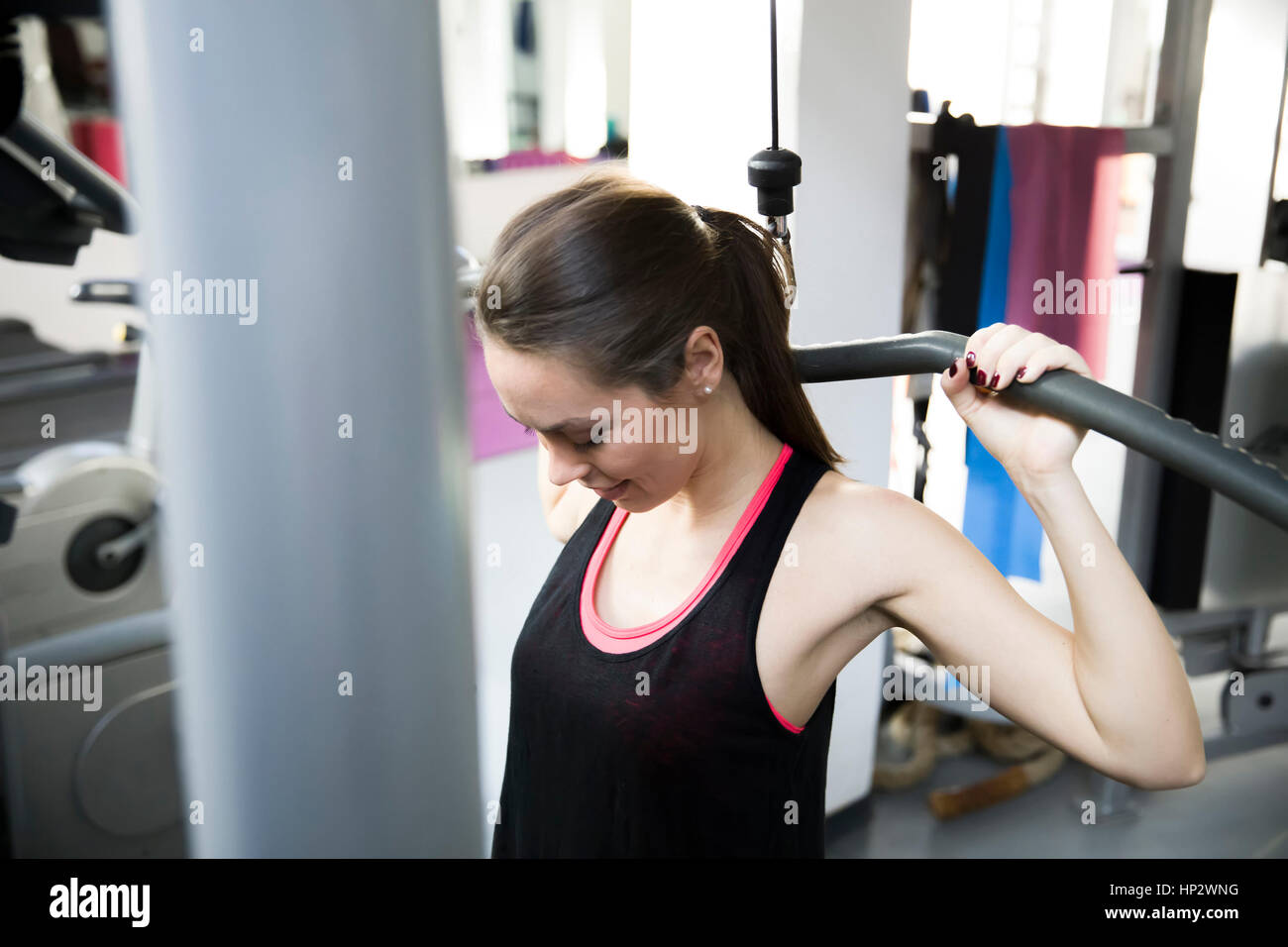 Attractive young woman working out on weight-lifting training machine ...