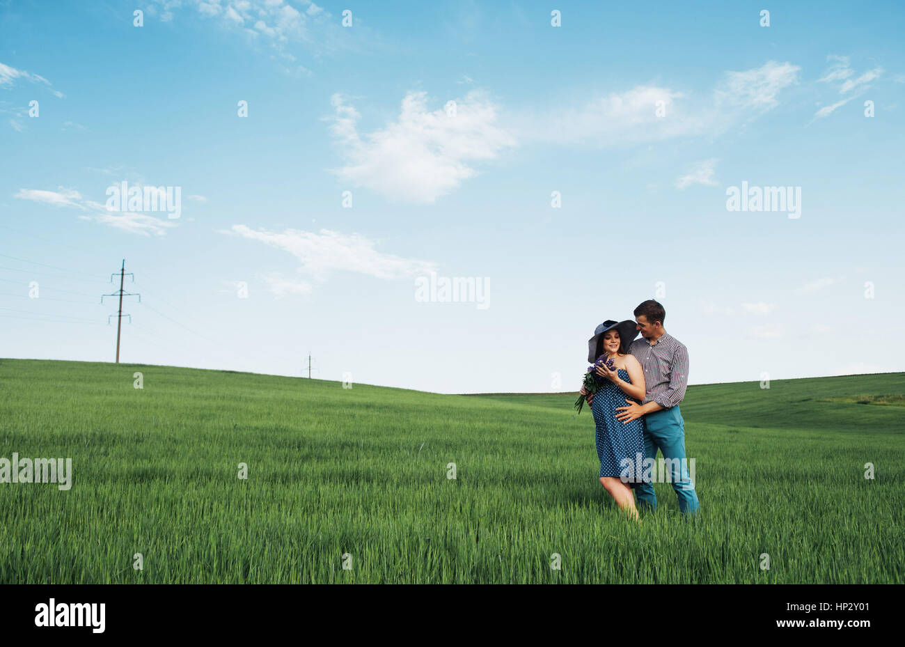 Happy family hugging in a field of green wheat Stock Photo - Alamy