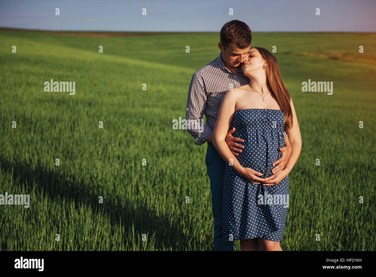 Happy family hugging in a field of green wheat Stock Photo - Alamy
