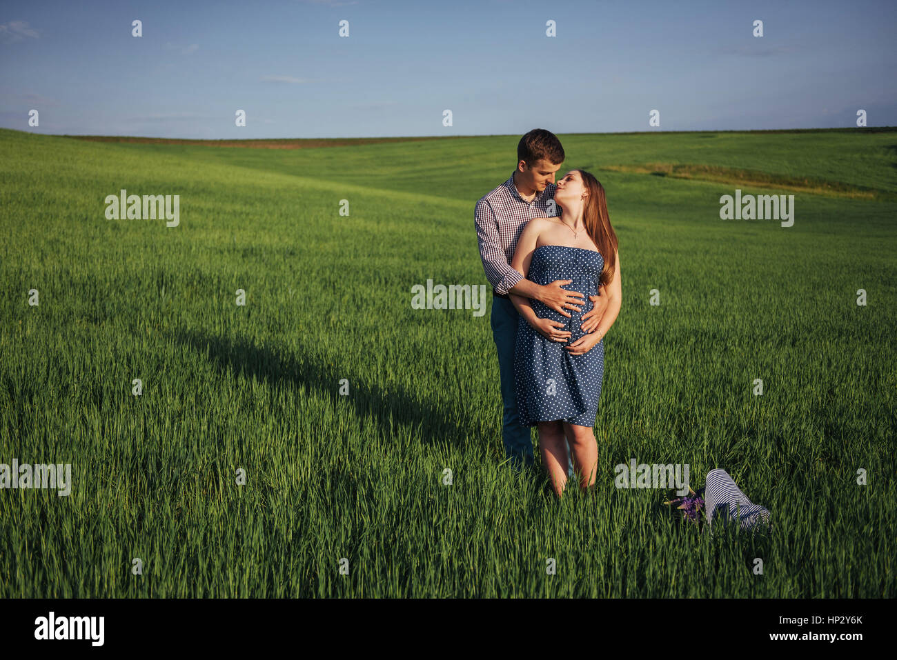 Happy family hugging in a field of green wheat Stock Photo - Alamy