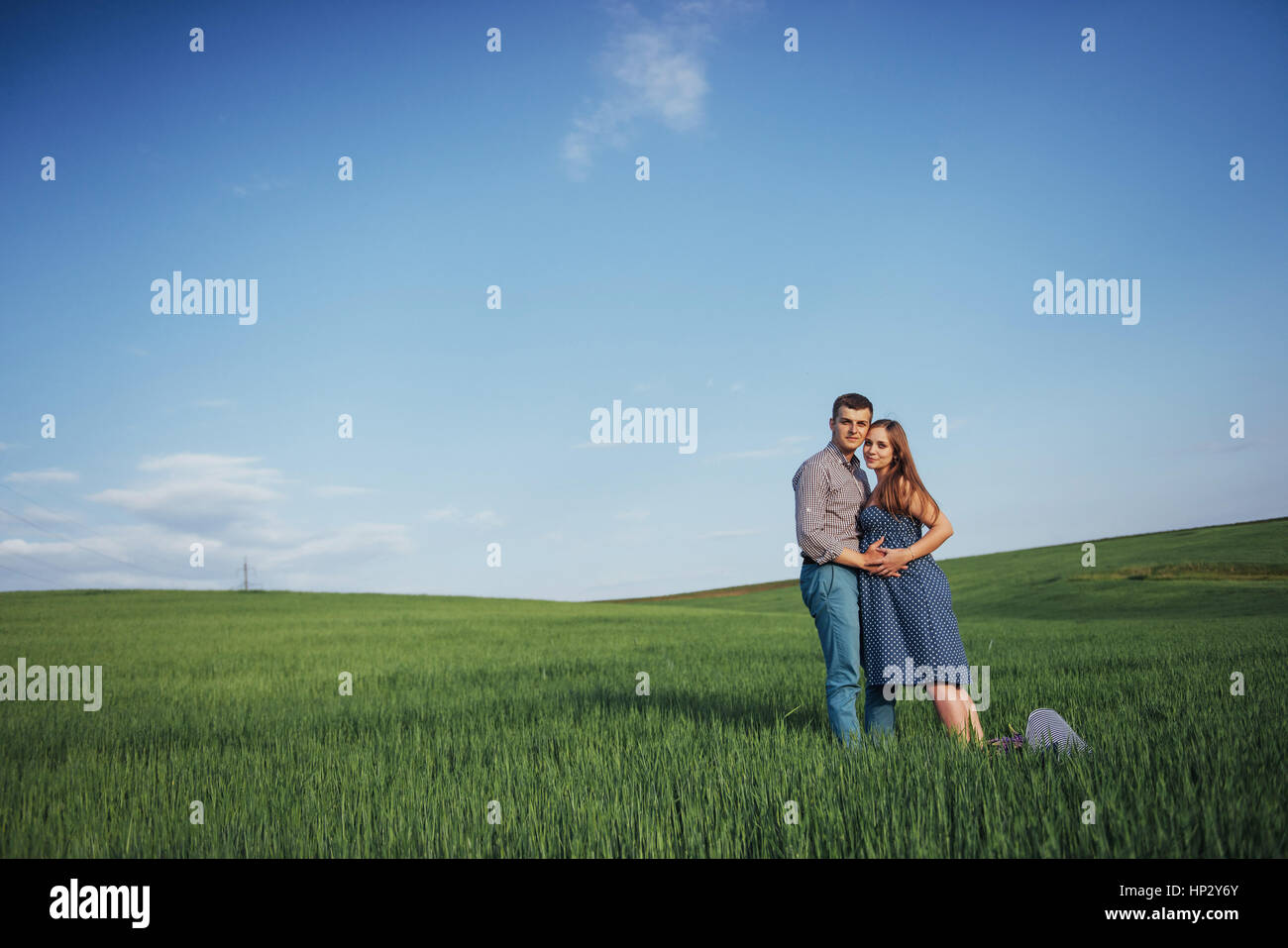 Happy family hugging in a field of green wheat Stock Photo - Alamy