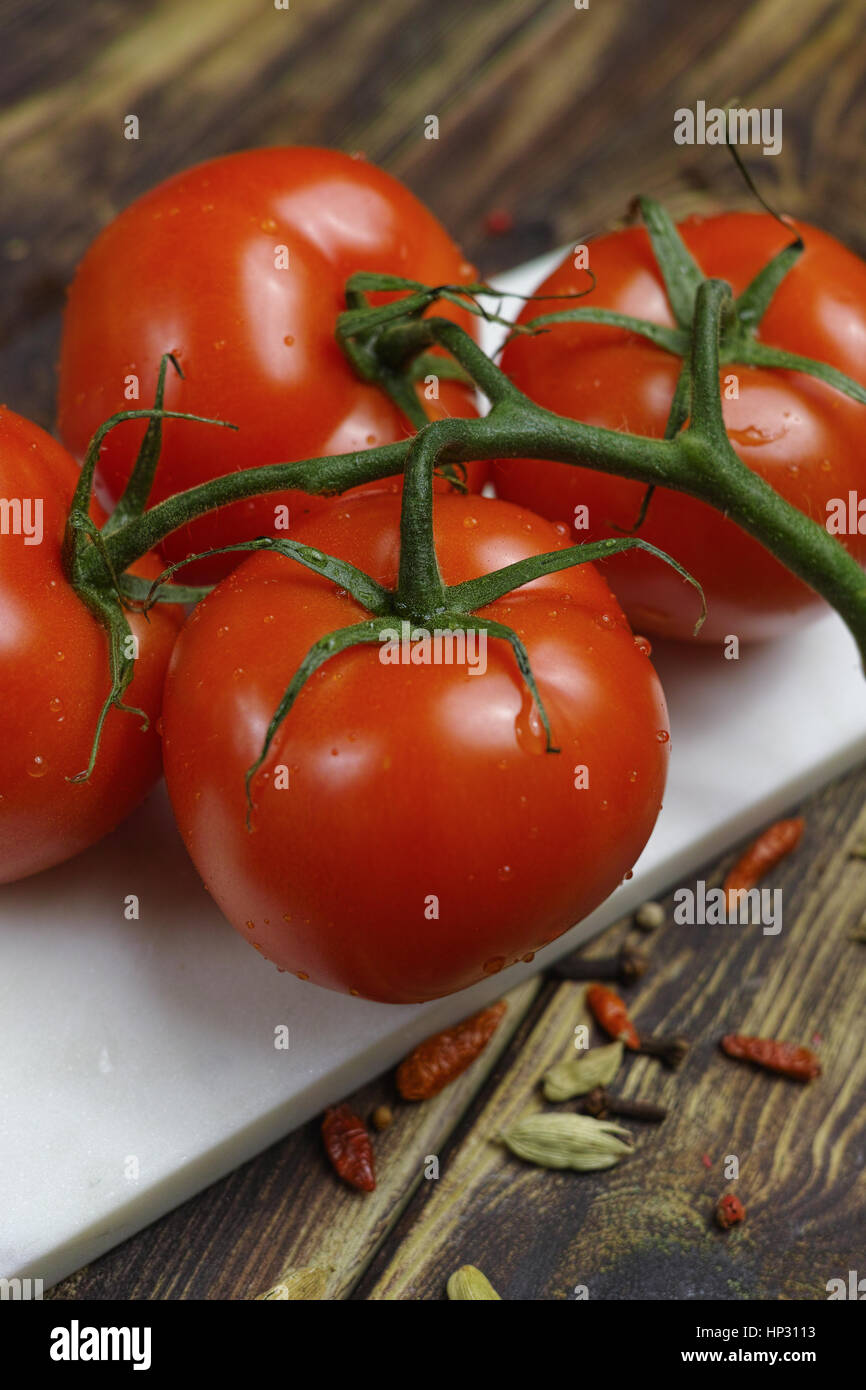 Raw Organic Red Tomatoes on the Vine on white marble plank Stock Photo ...