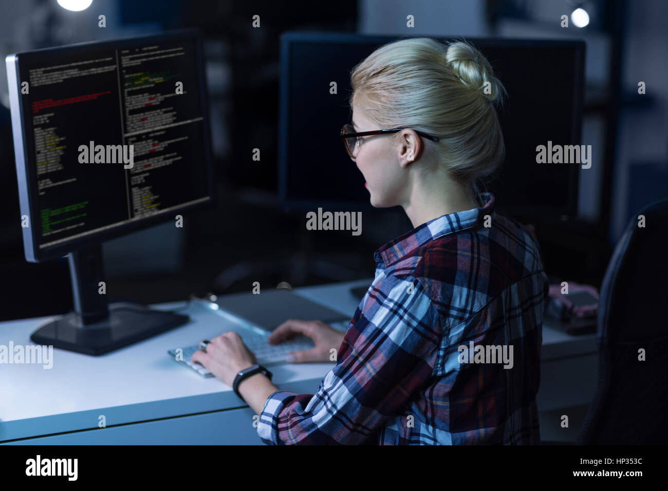 Attentive young IT girl decoding in the dark lighted room Stock Photo ...