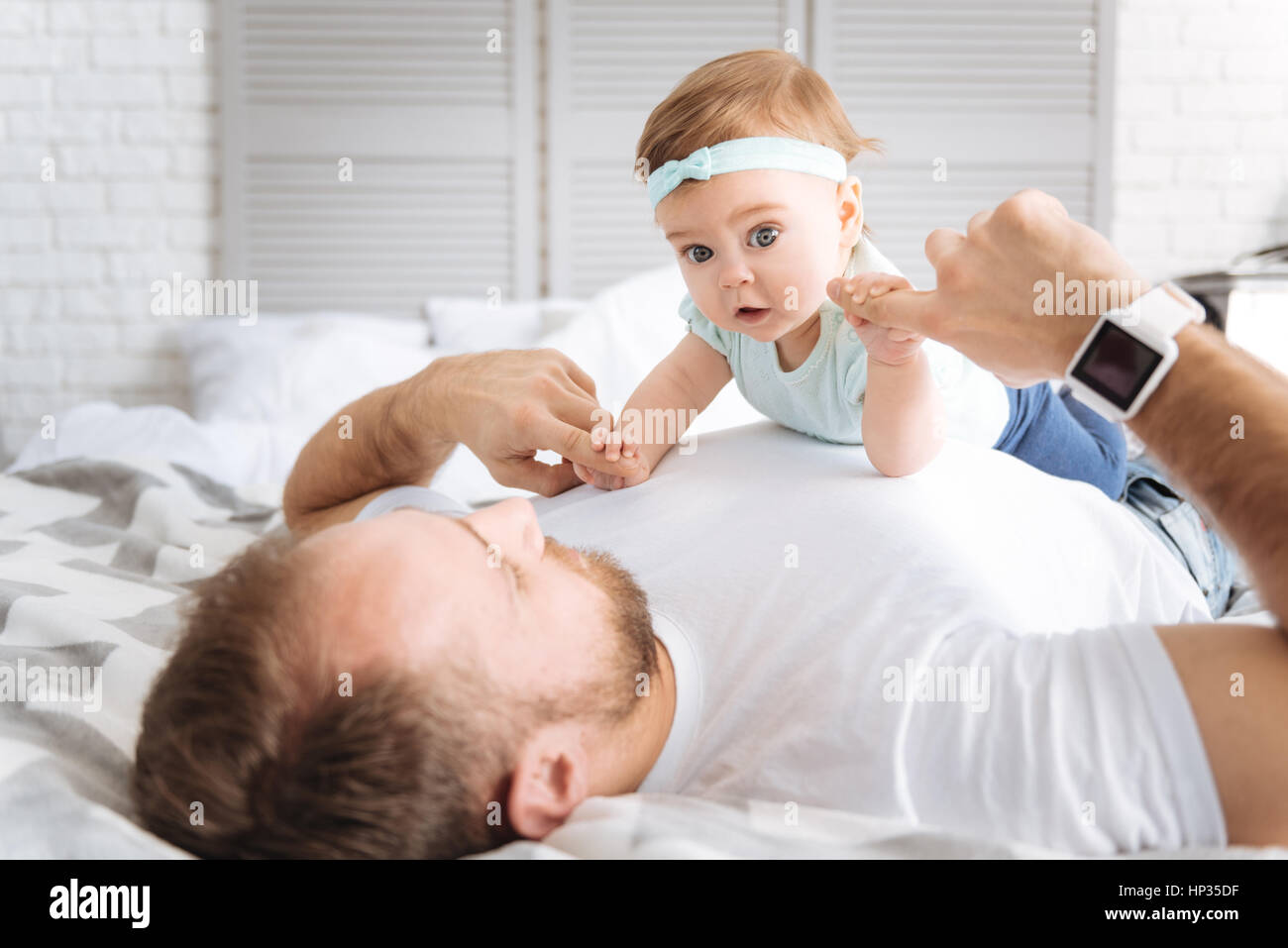Amused child lying on her father in the bedroom Stock Photo - Alamy