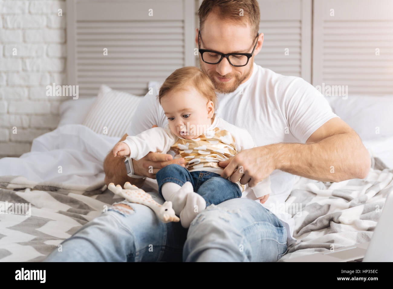 Helpful father wearing his little child at home Stock Photo - Alamy