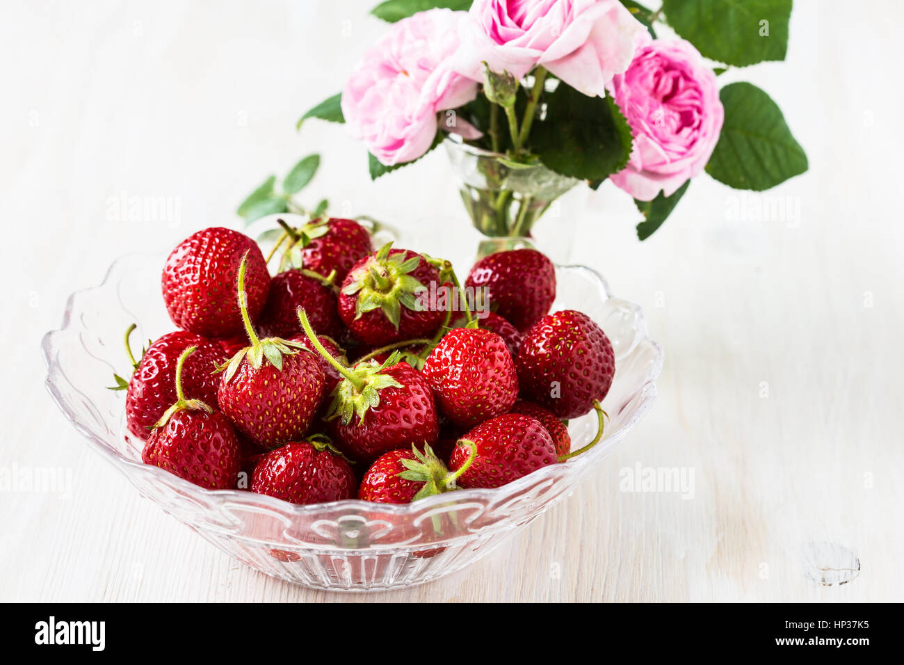 Romantic still life with strawberries and pink roses. Bunch of ripe ...
