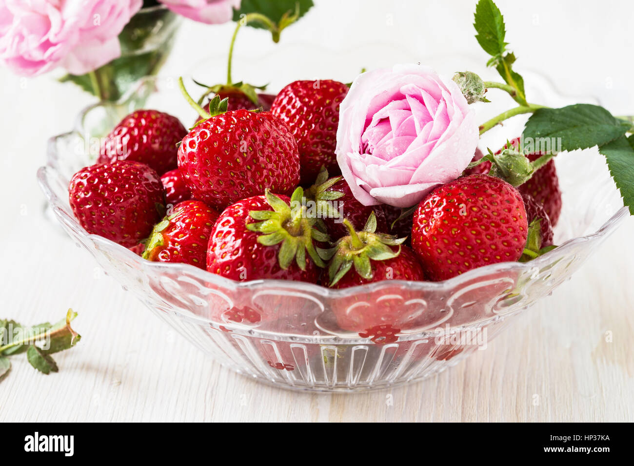 Romantic still life with strawberries and pink roses. Bunch of ripe ...