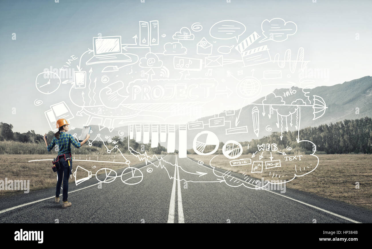 Back view of engineer woman in hardhat outdoor and sketched concept on ...
