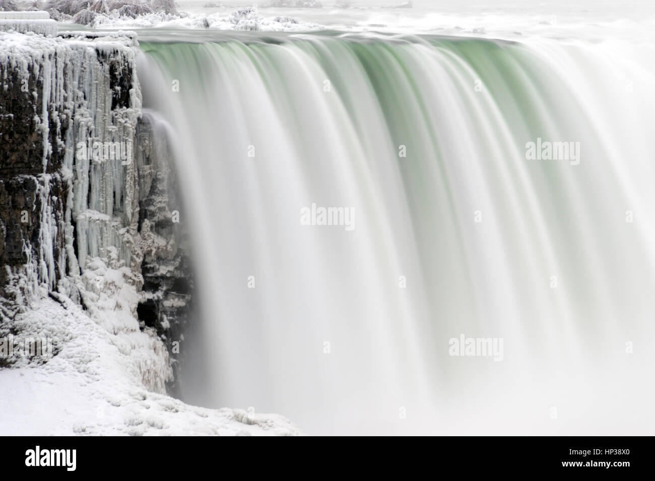 Closeup of strong waterfall flowing over ice covered cliff, smooth ...
