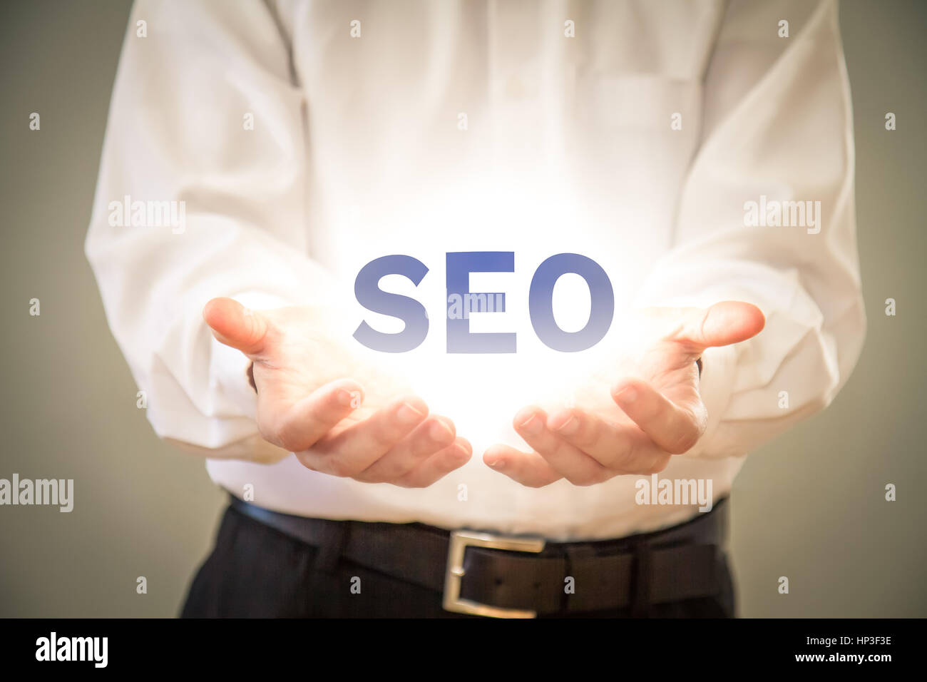 A business man with open hands holding a glowing word SEO which stands ...
