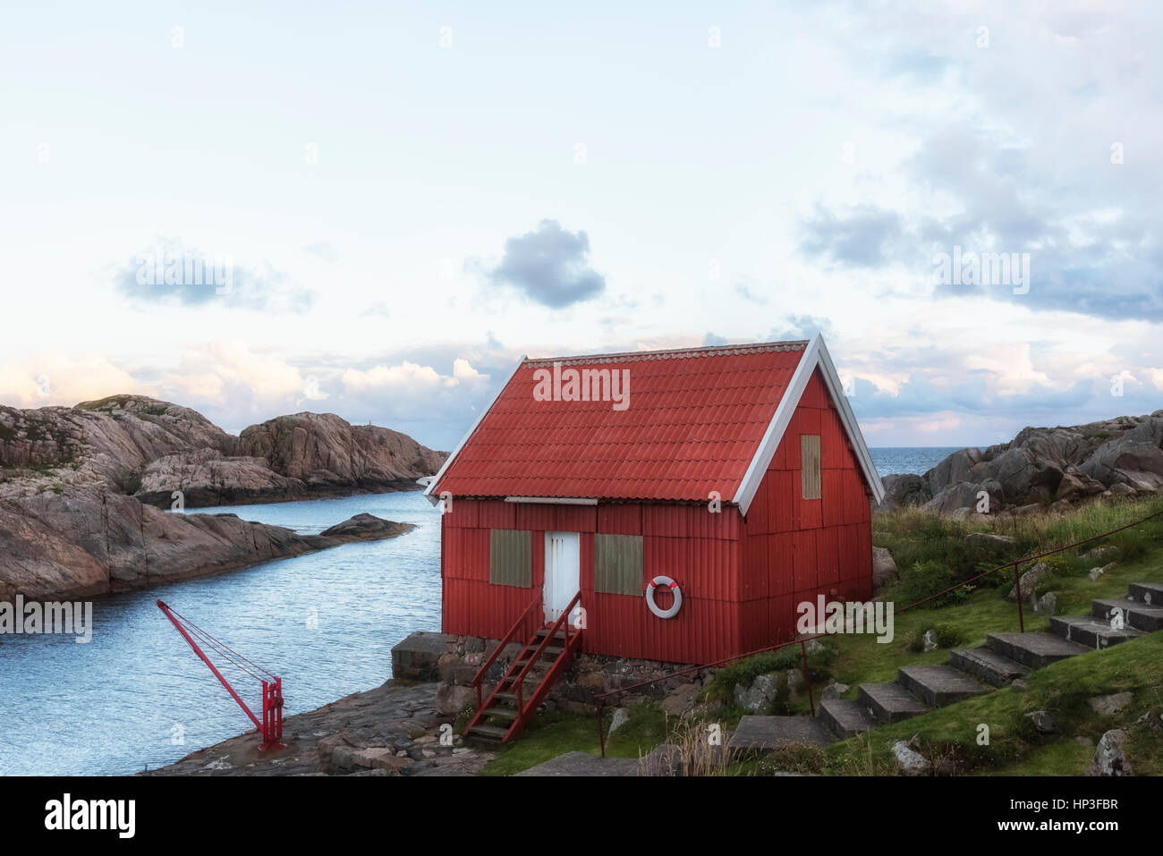 A colourful red shed at the coast of Lindesnes - Norway - during sunset ...