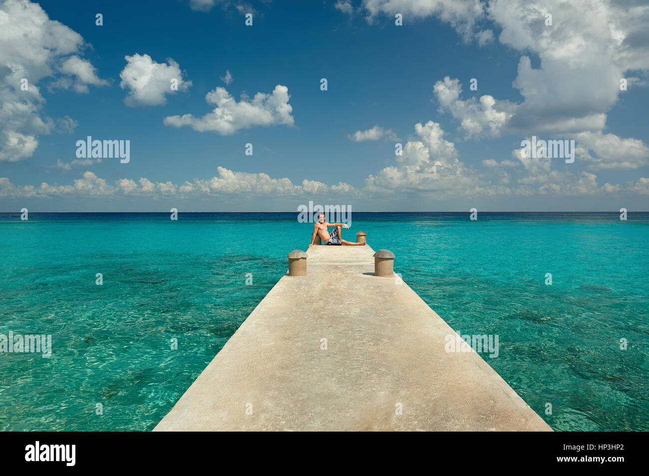 Young man sit on pier in caribbean blue water background. Pier in ...