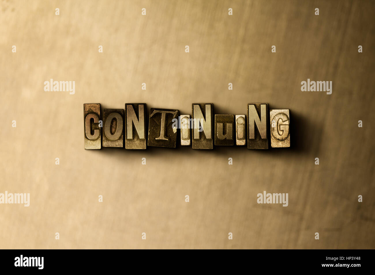 CONTINUING - close-up of grungy vintage typeset word on metal backdrop ...