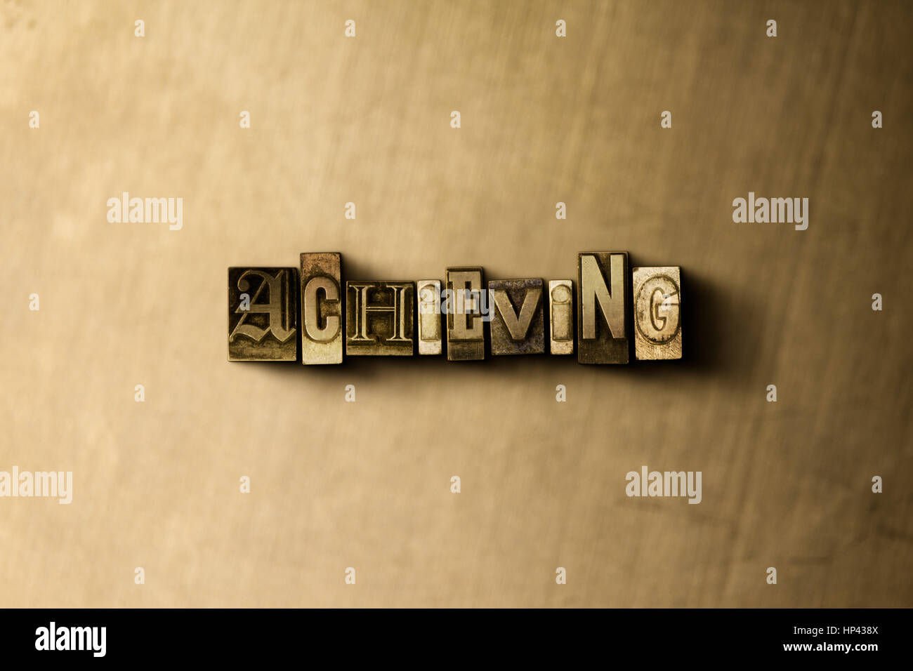 ACHIEVING - close-up of grungy vintage typeset word on metal backdrop ...