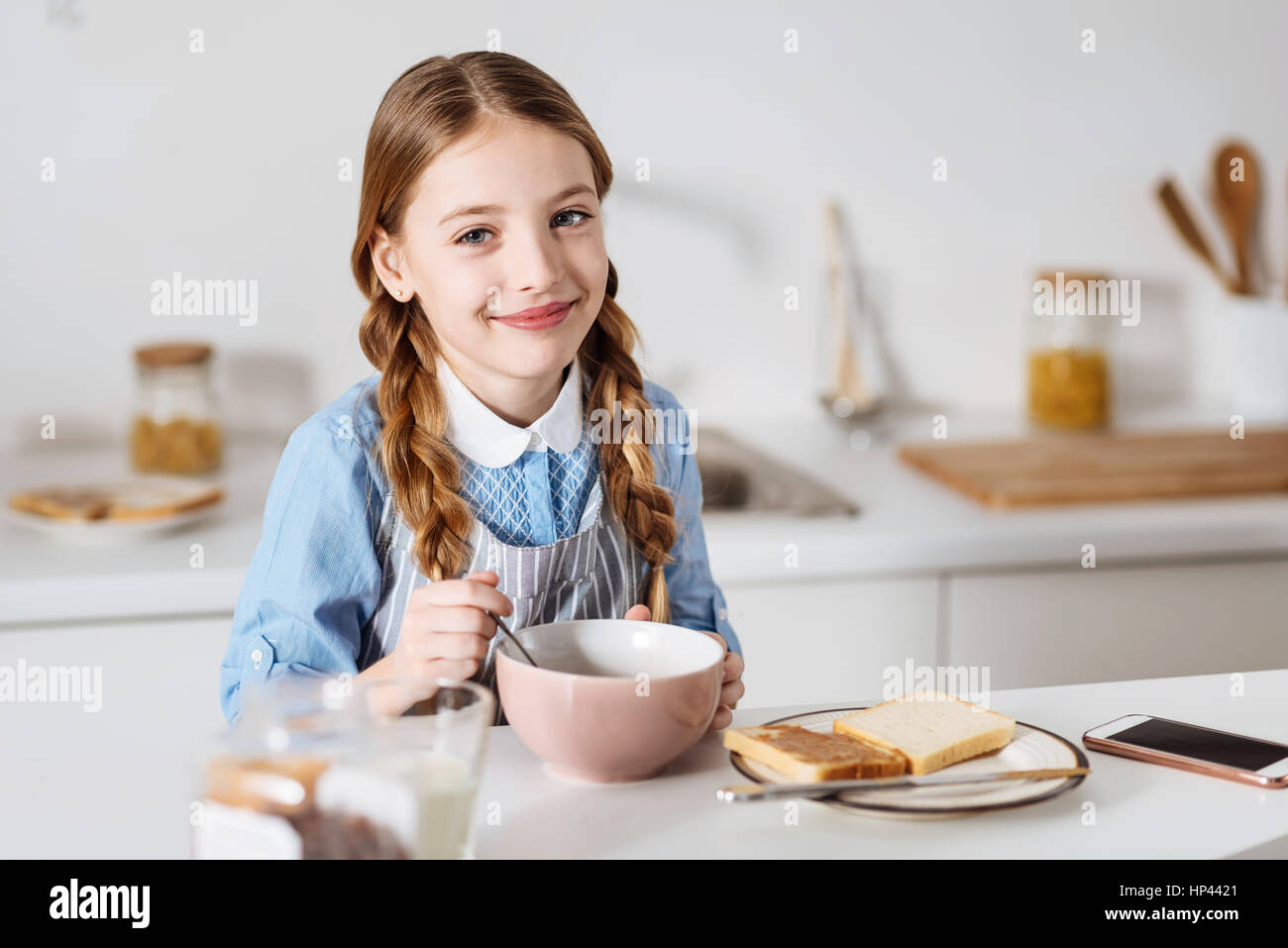 Beautiful girl looking delighted while eating breakfast Stock Photo - Alamy