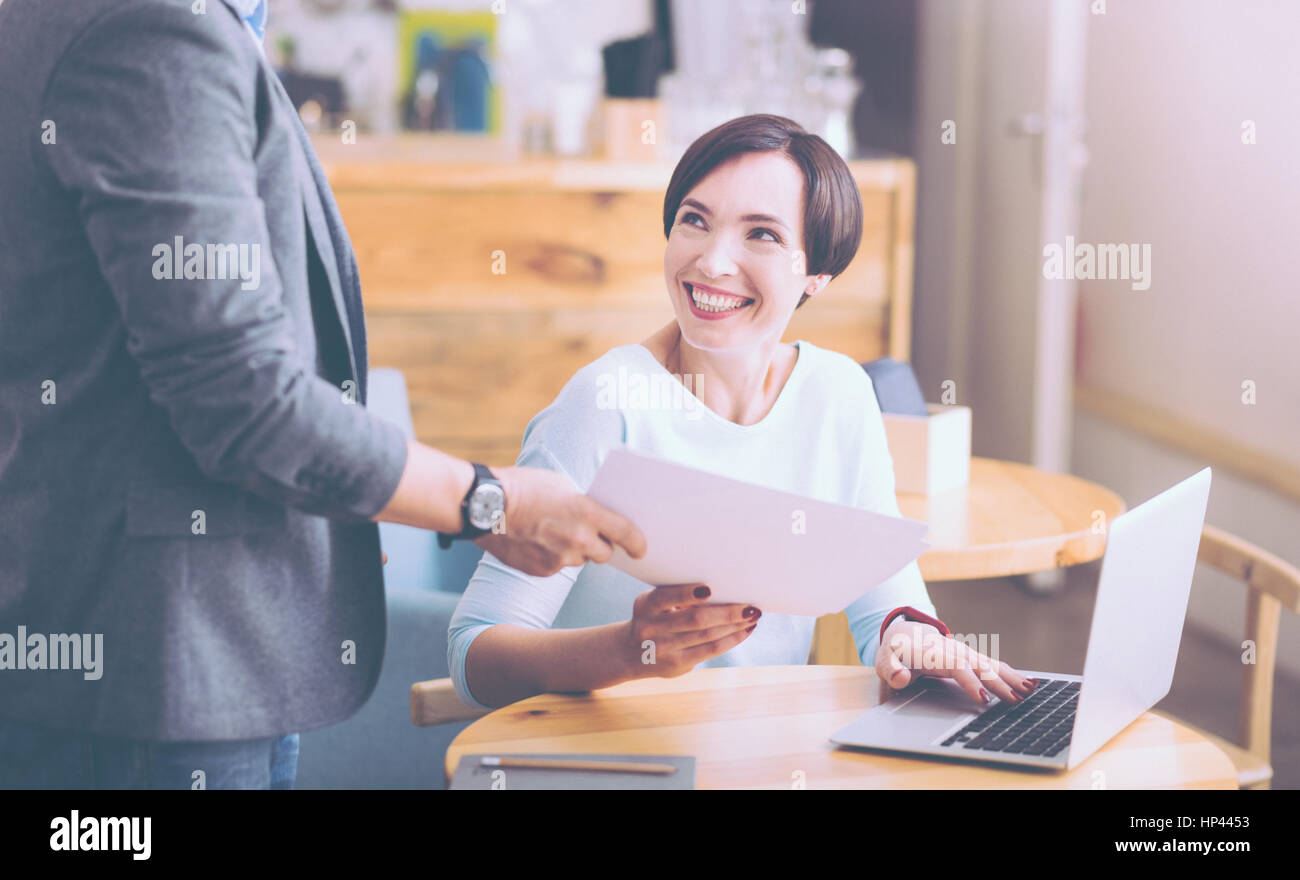 Cheerful woman getting papers from her collegue Stock Photo - Alamy