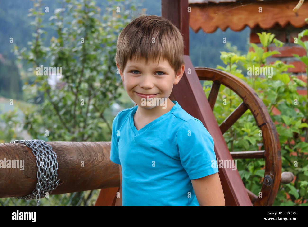 Smiling boy in front of old style wooden well Stock Photo - Alamy