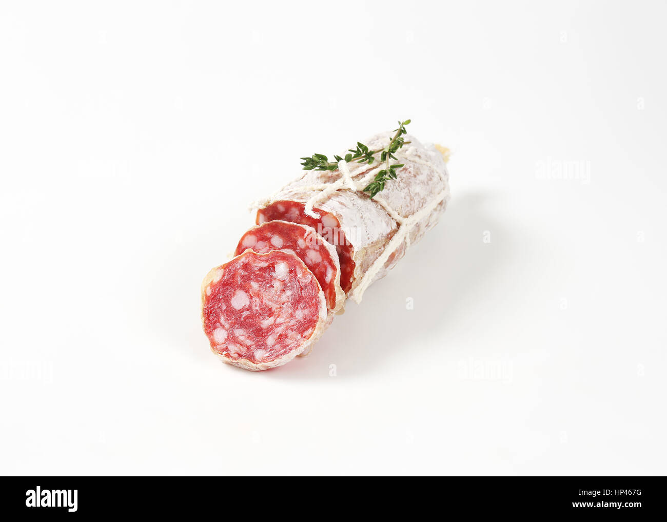 sliced french dry salami and thyme on white background Stock Photo - Alamy