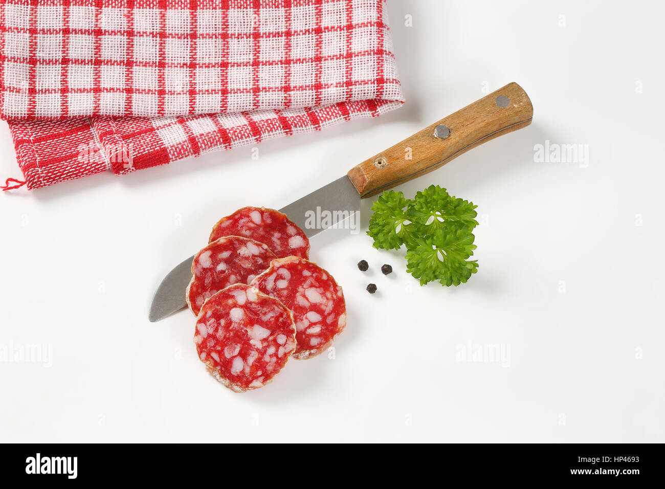 thin slices of french dry salami, kitchen knife and spices on white ...