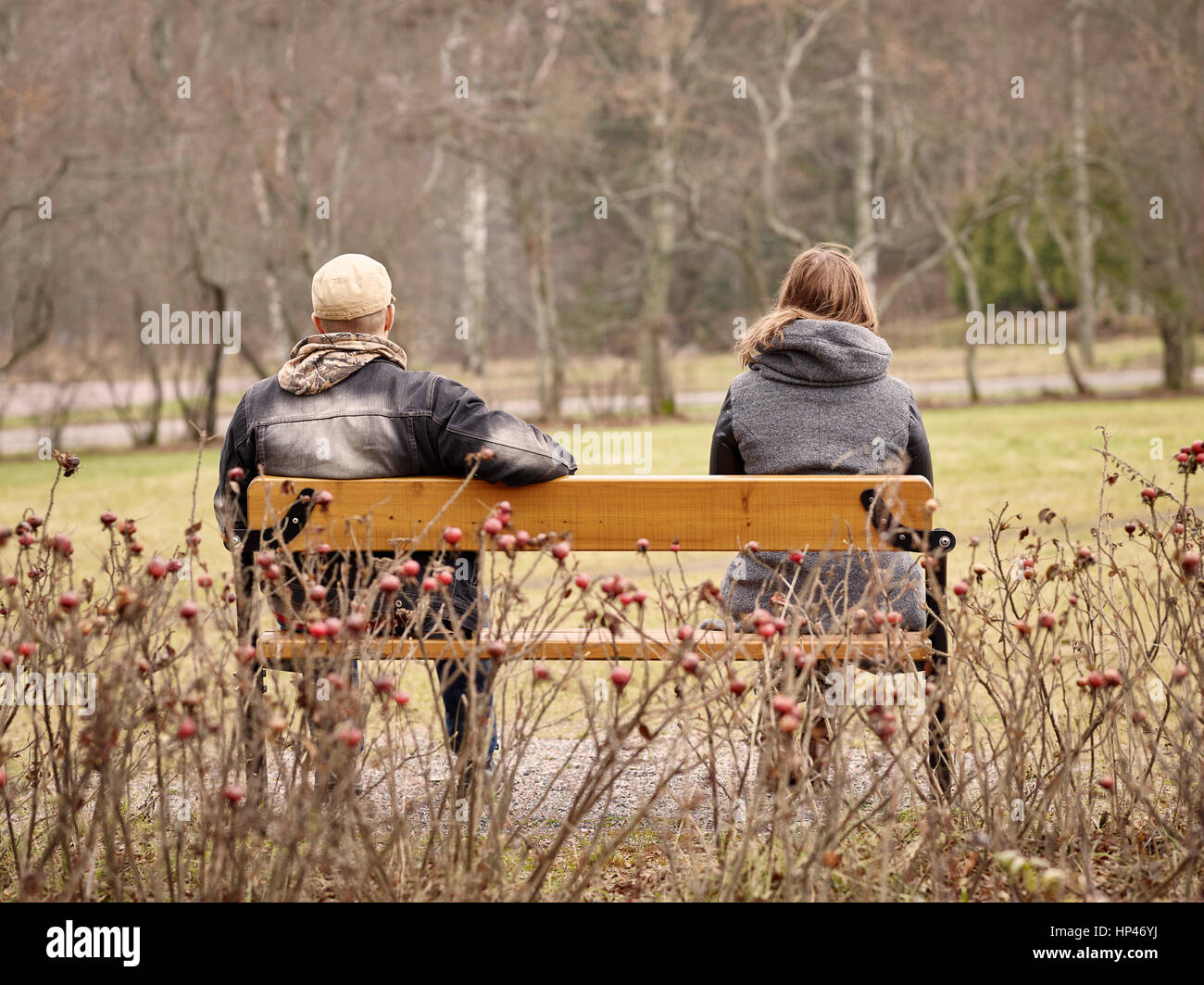 Man and a woman sitting on a park bench hi-res stock photography and ...