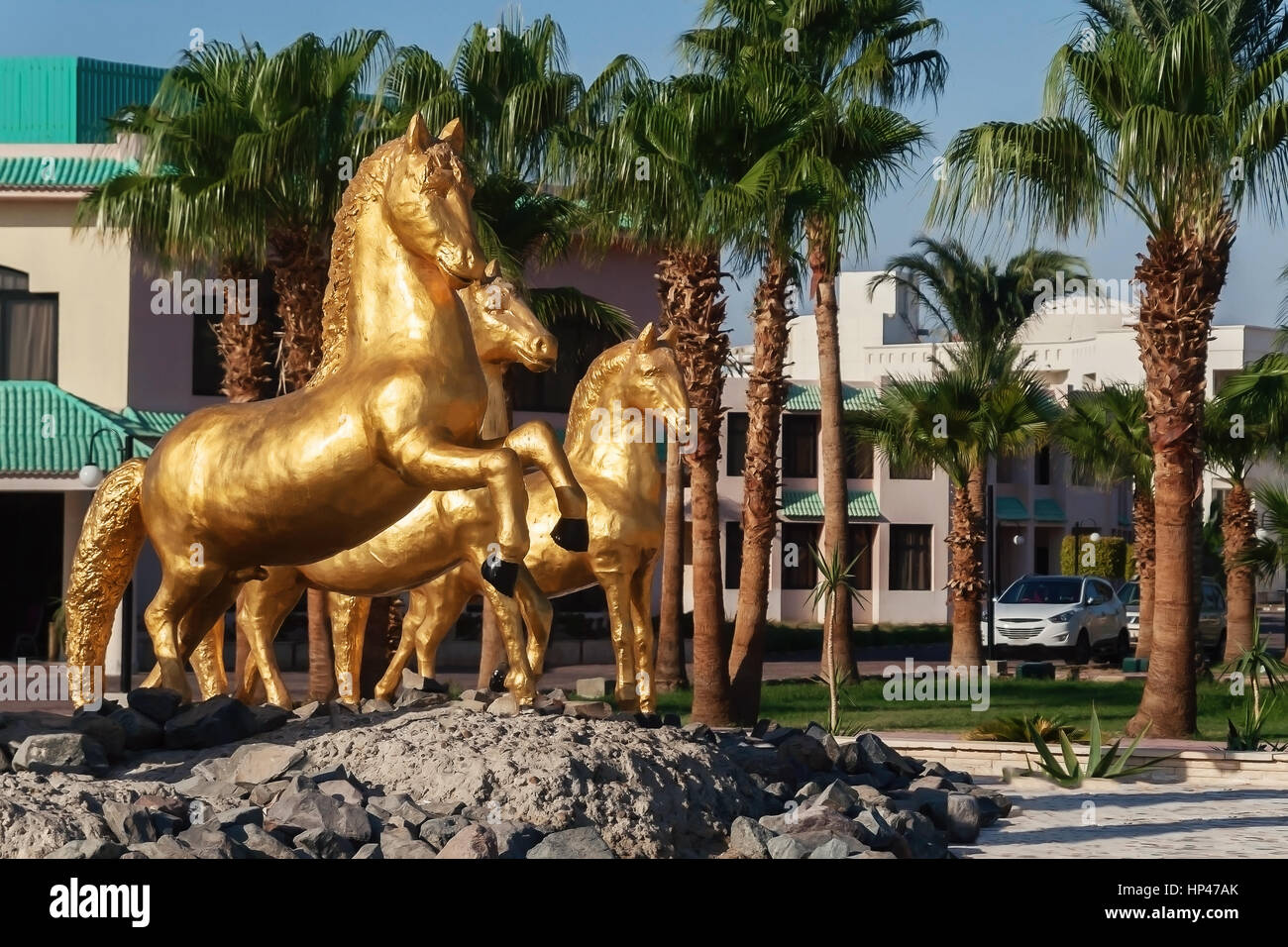 three gold statue of a horse on a background of palm trees Stock Photo ...