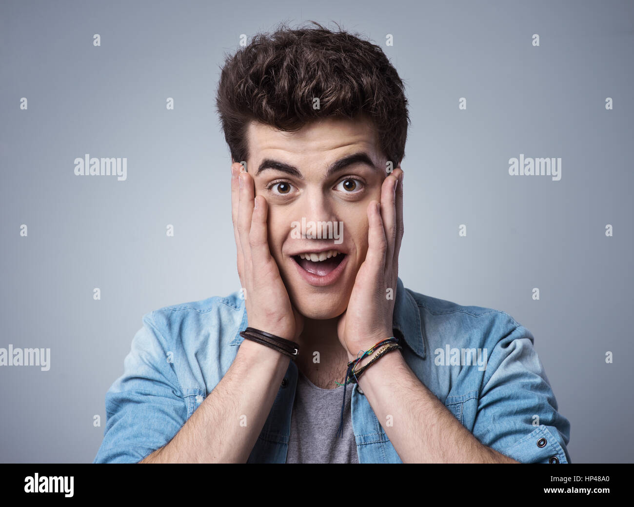 Terrified funny teenager boy head in hands on gray background Stock ...