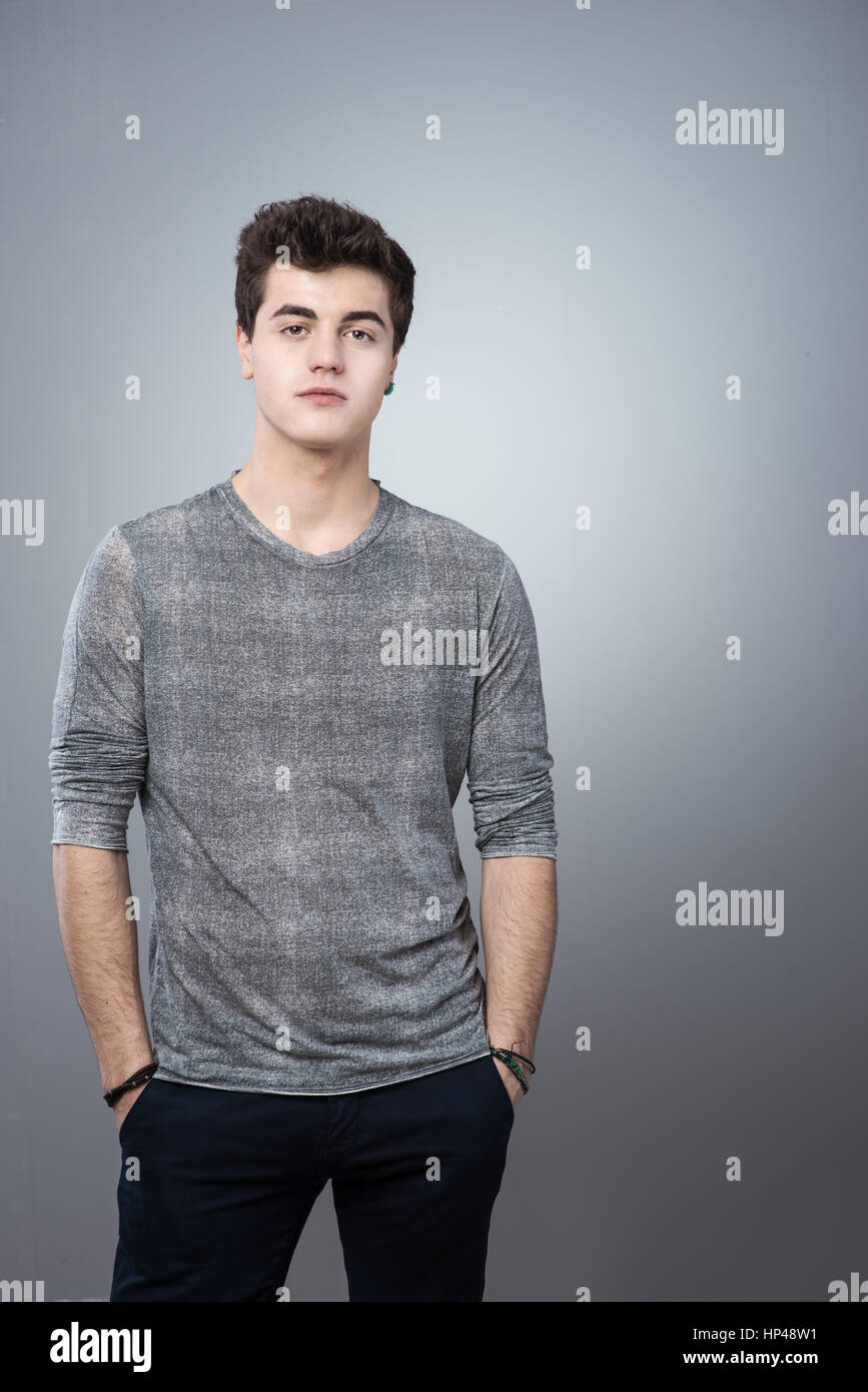 Cool guy standing with hands in pockets against gray background Stock ...