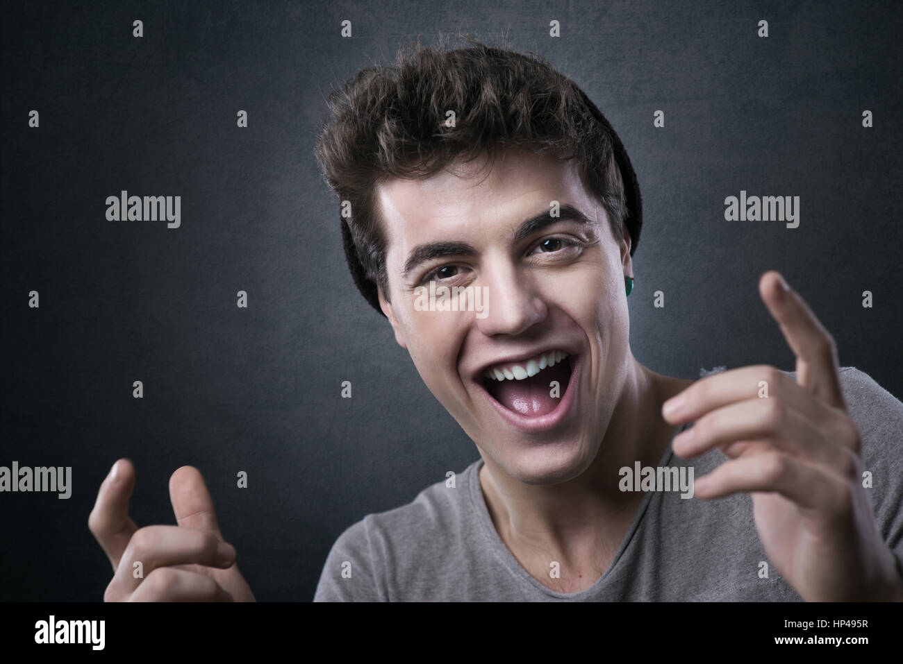 Excited cheerful young man smiling at camera with hands raised Stock ...