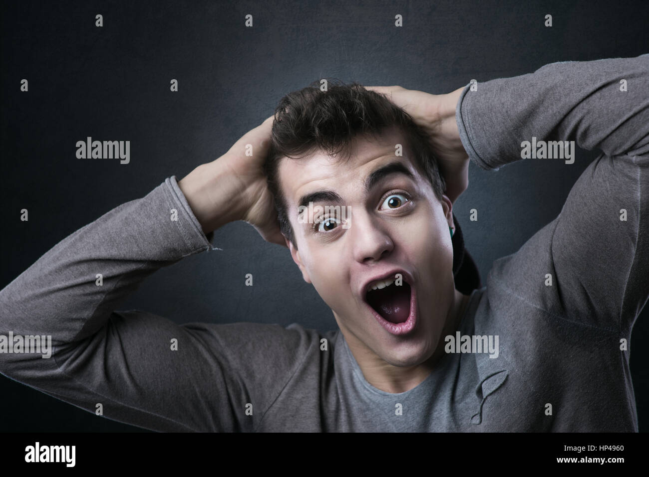 Joyful excited young man with head in hands receiving surprising good ...