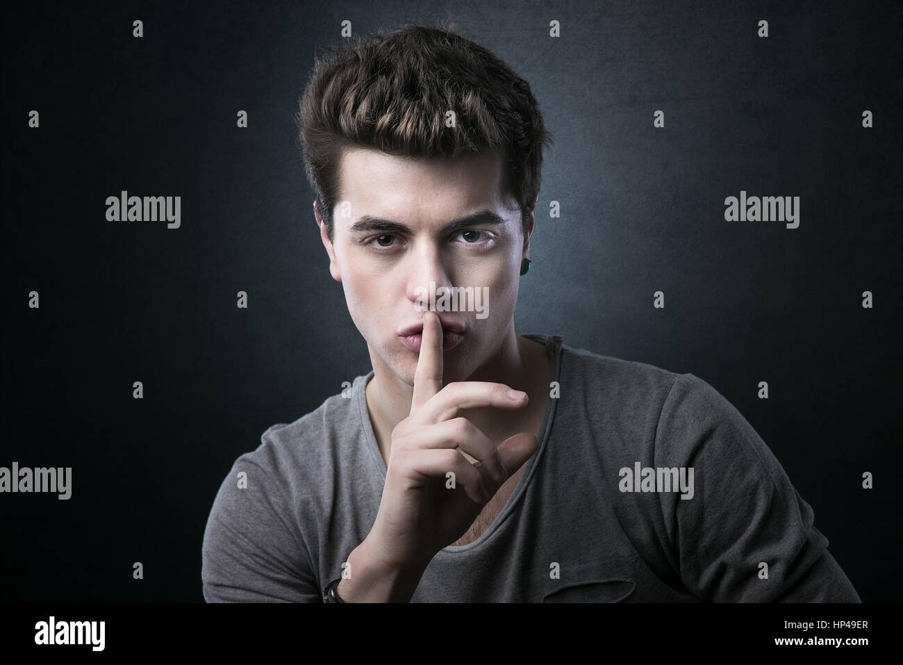Young handsome man making silence gesture and looking at camera Stock ...