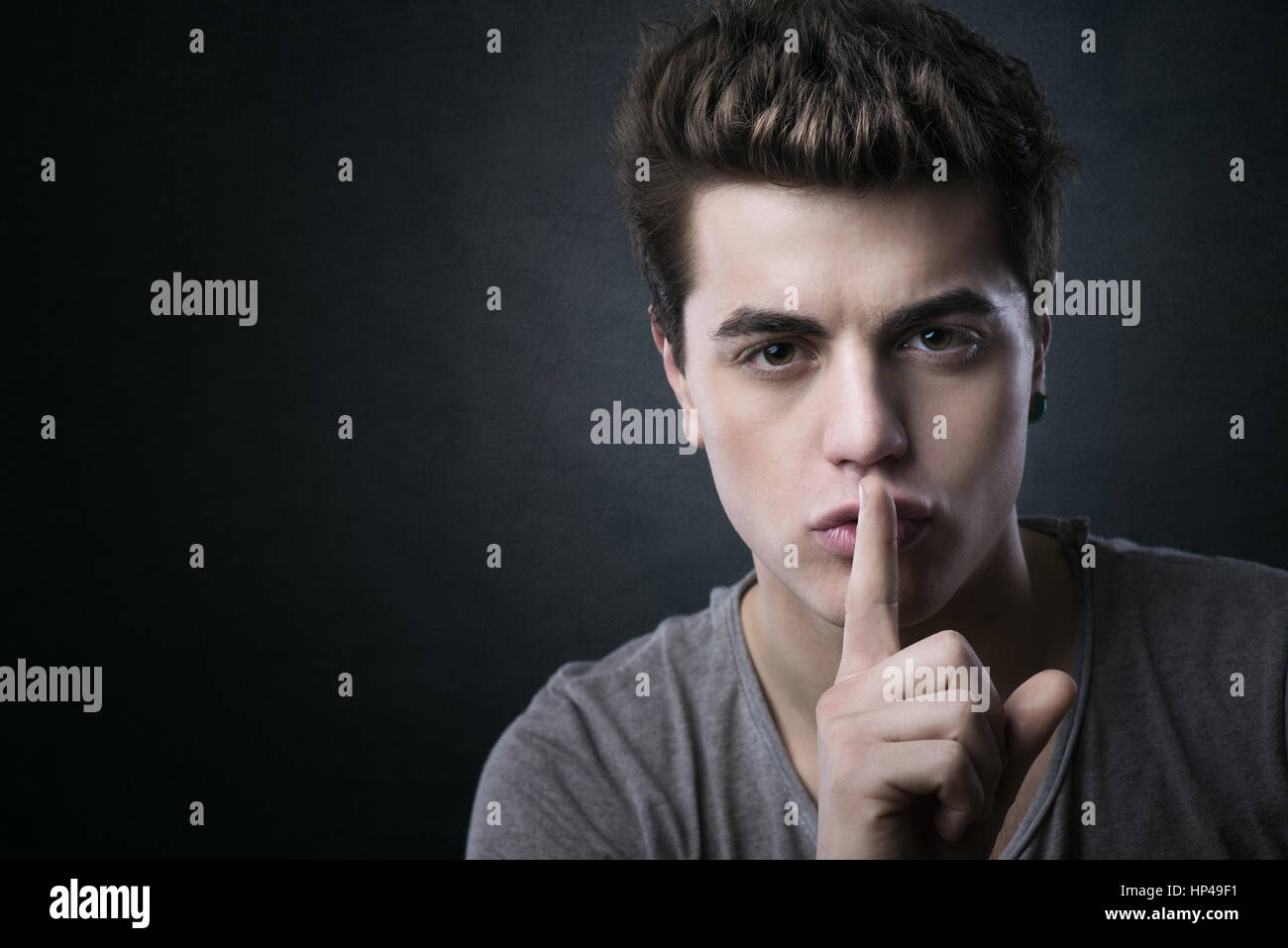 Young handsome man making silence gesture and looking at camera Stock ...