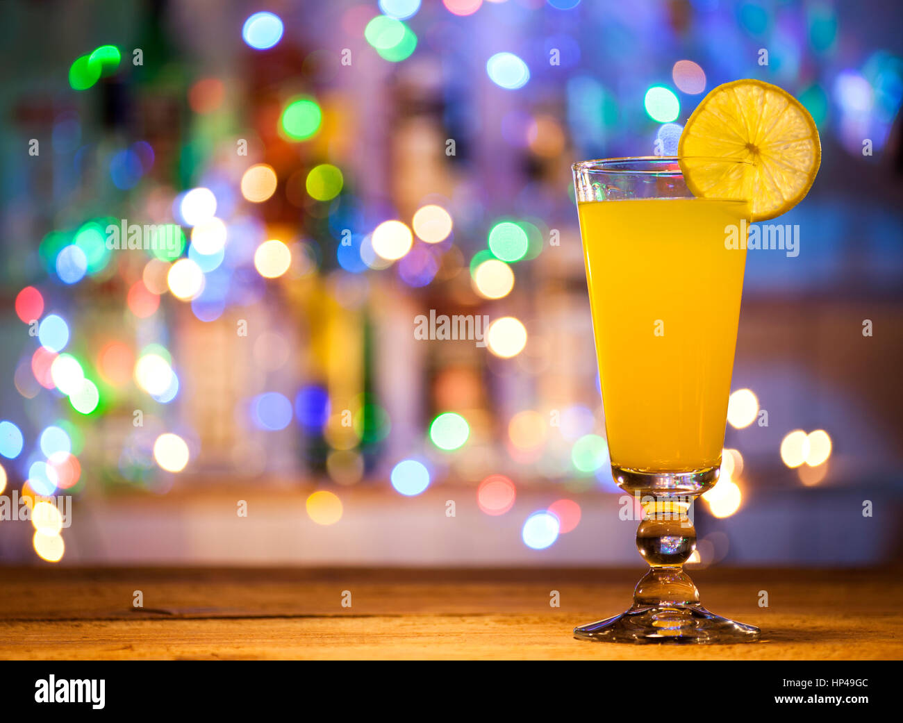 Glass of orange cocktail on a bar lights background Stock Photo - Alamy