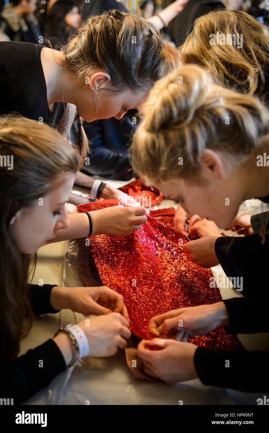 Seamstresses adjust clothes backstage before the Julien Macdonald ...