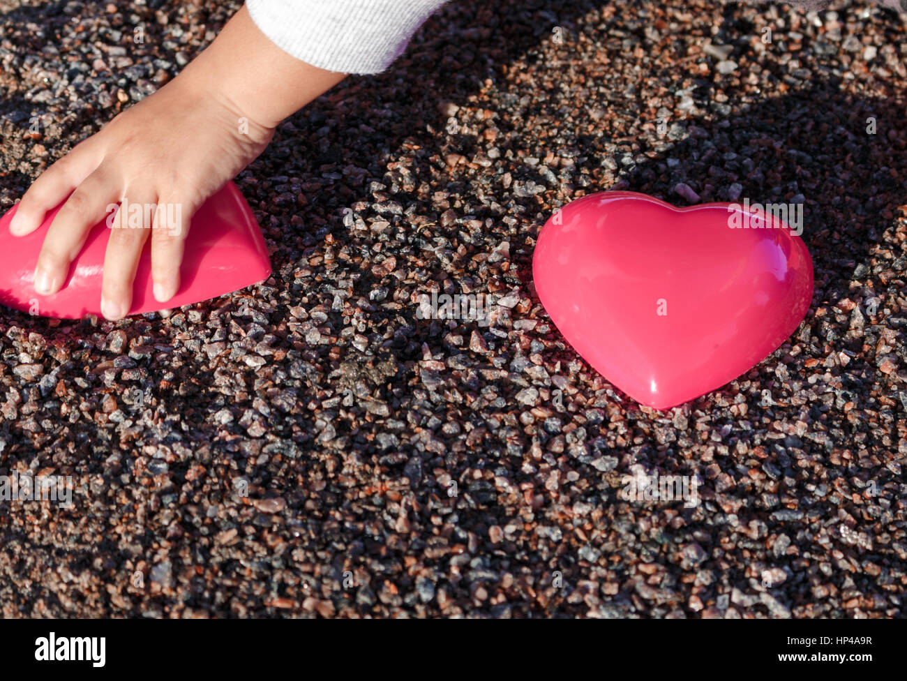 Red plastic heart lies on the sand. pea gravel Stock Photo - Alamy