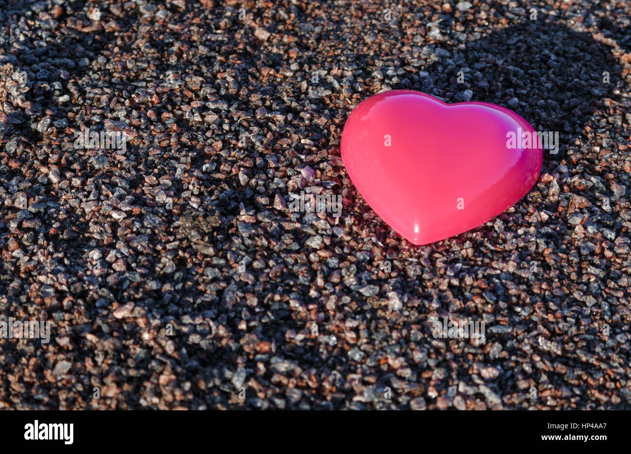 Red plastic heart lies on the sand. pea gravel Stock Photo - Alamy