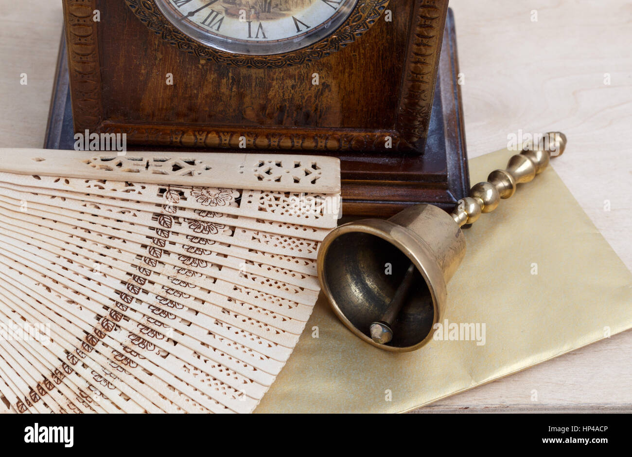 still life, brass bell, antique clock and carved wooden fan Stock Photo ...