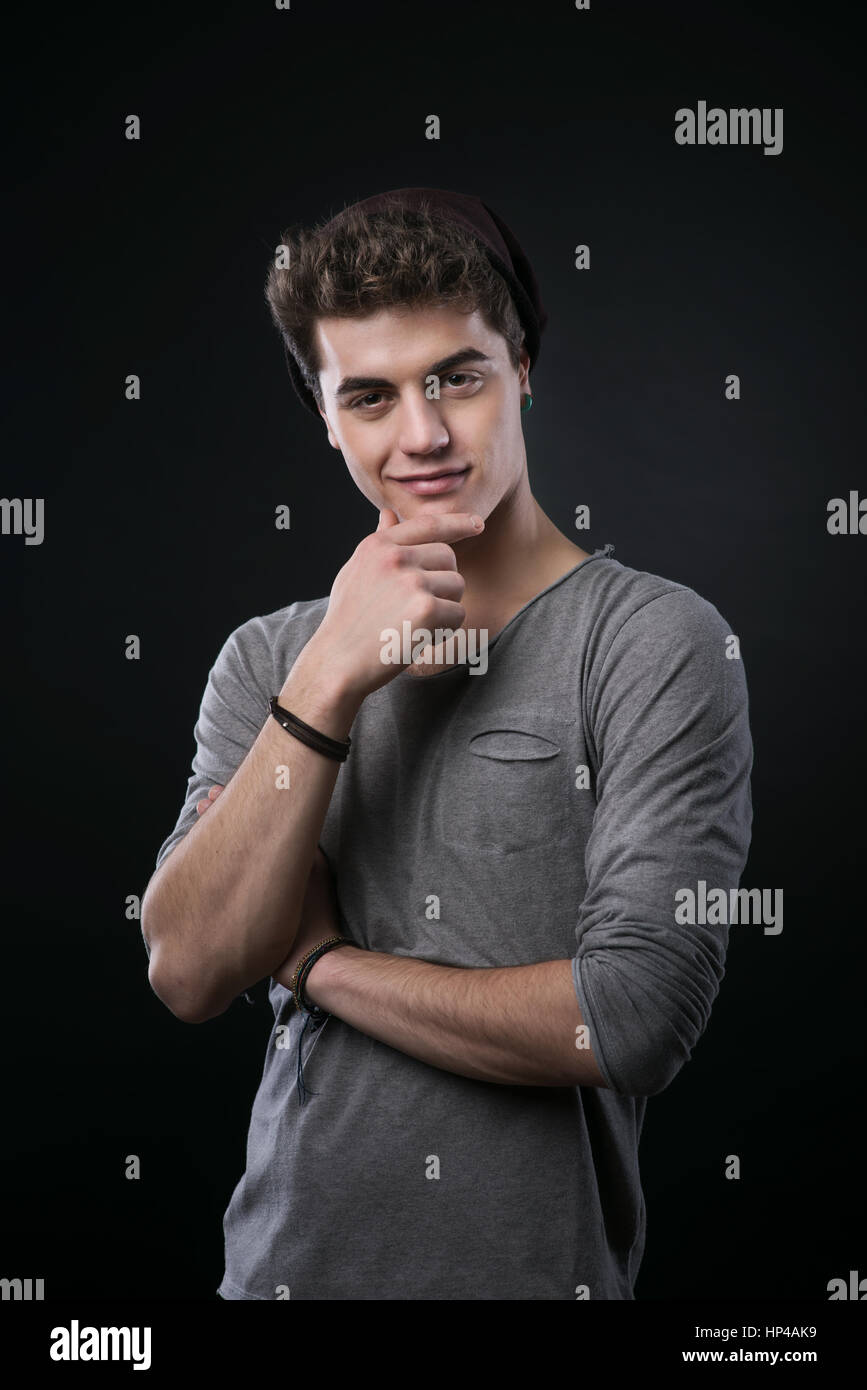 Smirking young attractive man posing with hand on chin Stock Photo - Alamy