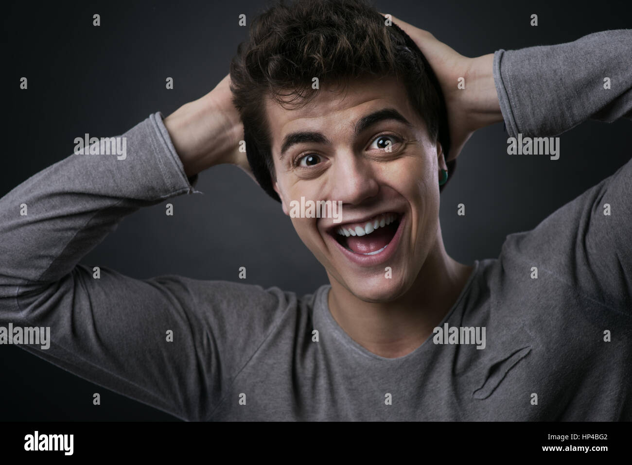 Joyful excited young man with head in hands receiving surprising good ...