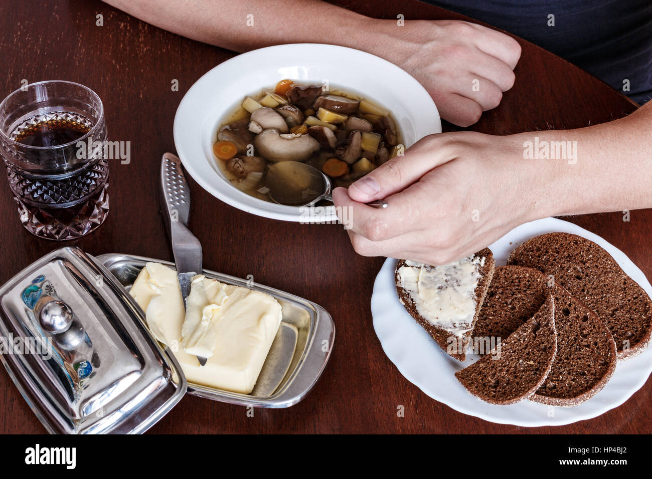 man eating soup with his left hand. left-handed. mushroom soup. bread ...