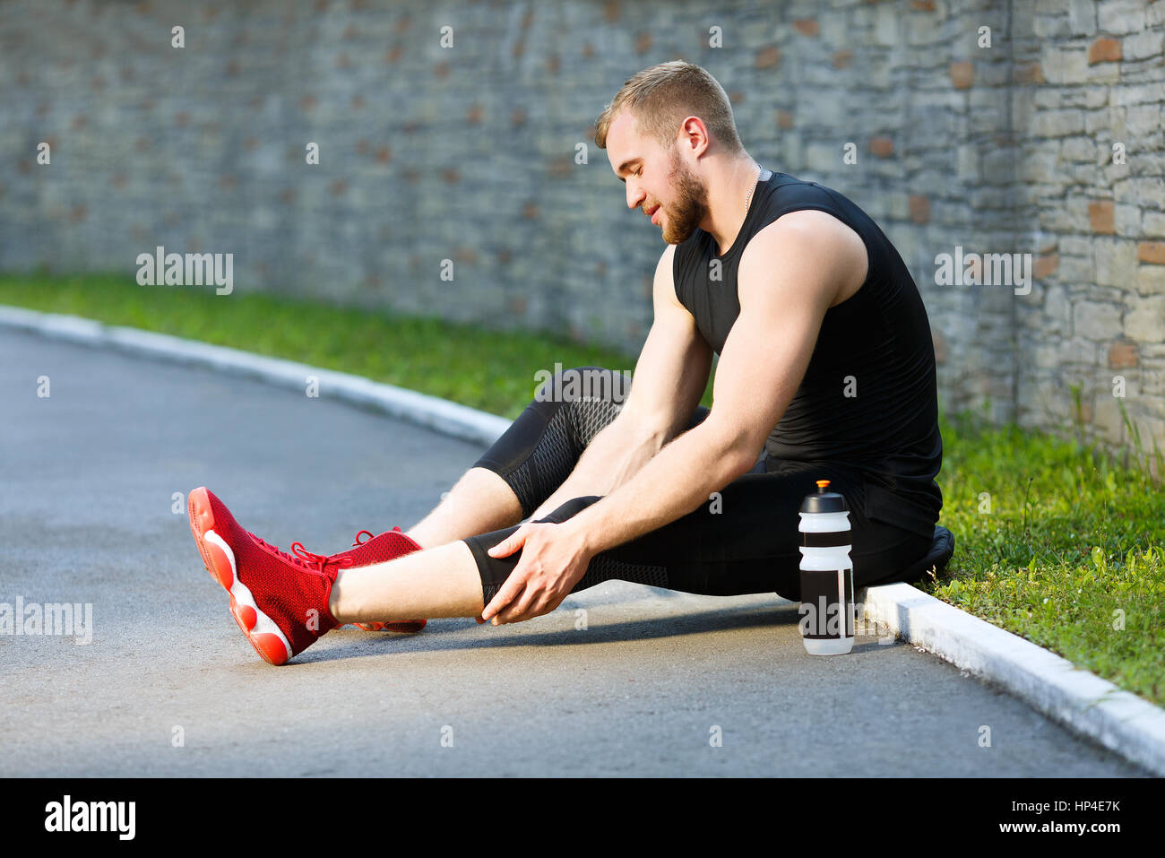Man sitting and holding his leg Stock Photo - Alamy